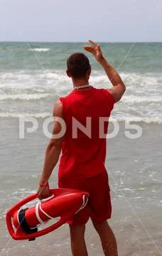 Muscular lifeguard on the shore of the sea in the beach of tourist ...