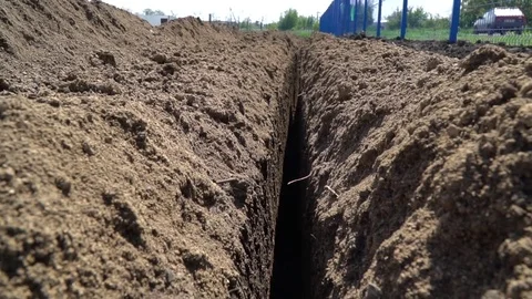 A narrow earth trench on the constructio... | Stock Video | Pond5