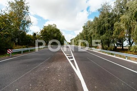 New asphalt road with markings and road signs in the sun's rays ...
