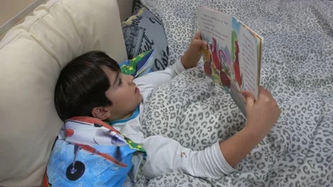 At night a child is reading a book befor... | Stock Video | Pond5