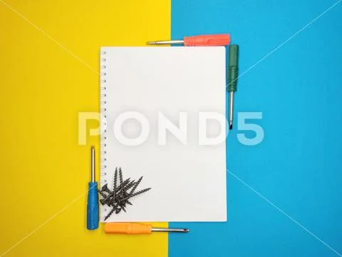 Notepad with screws in the lower left corner on a yellow and blue ...