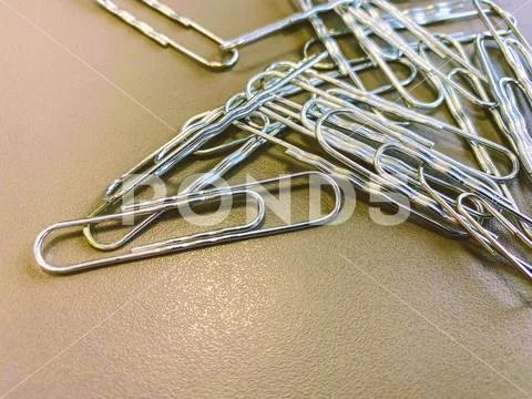 Office tools. metal paper clips lie on a dark, matte background. paper ...