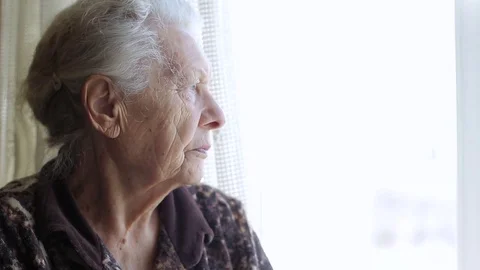 The old lady looks out the window. | Stock Video | Pond5