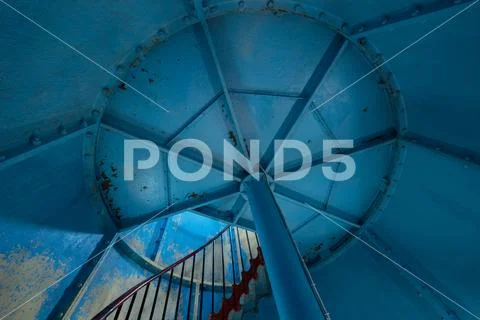 Old lighthouse on the inside. Red iron spiral stairs and blue wall ...