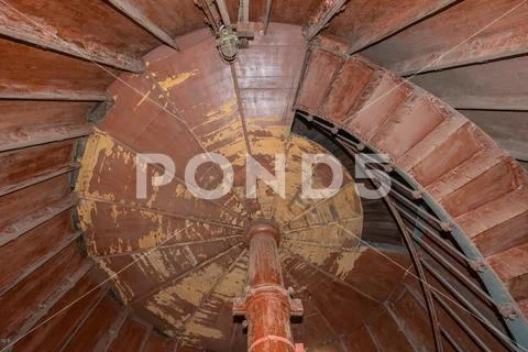 Old lighthouse on the inside. Red iron spiral stairs, round window and ...