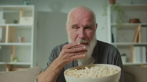 An Old Man Eating Popcorn and Concentrat... | Stock Video | Pond5