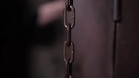 An old metal chain in a dark room, a man... | Stock Video | Pond5
