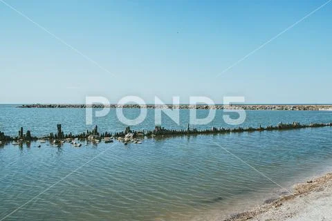 An old ruined pier with wooden logs sticking out of the water from the ...