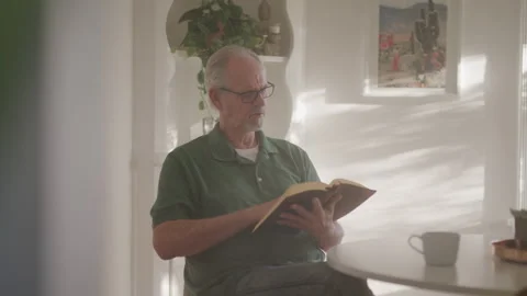 Older Man Reading Book At Table | Stock Video | Pond5