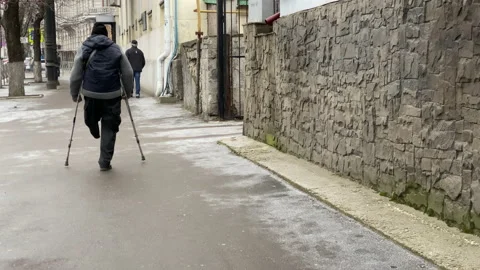 one-legged disabled man walking with cru... | Stock Video | Pond5