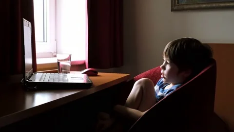 One little boy sits at a table using lap... | Stock Video | Pond5