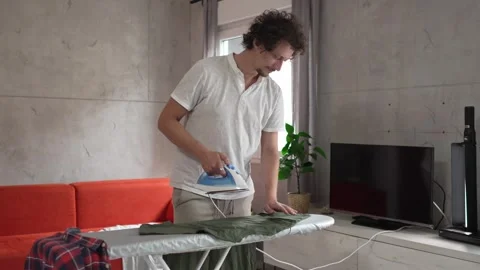 one man ironing clothes at home hold iro... | Stock Video | Pond5