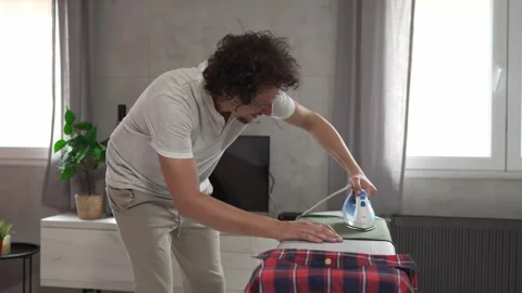 one man ironing clothes at home hold iro... | Stock Video | Pond5