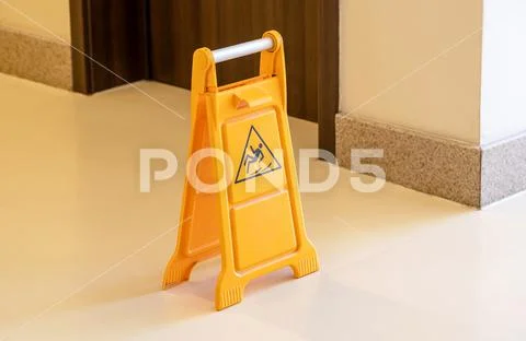 One orange caution slippery wet floor fold out sign in the hallway ...