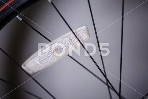 One plastic white reflector on gray metal spokes of a black wheel on a ...