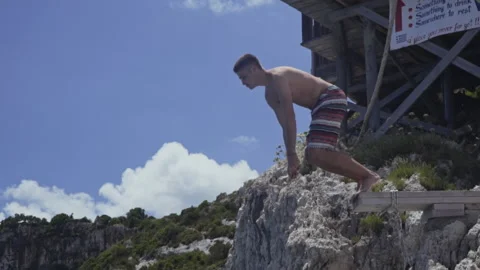 Onlookers watch man dive off platform in... | Stock Video | Pond5