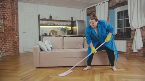 Overweight woman cleaning floor in livin... | Stock Video | Pond5