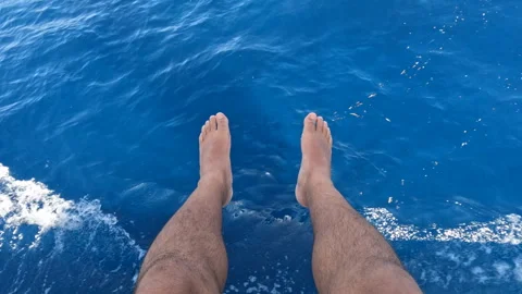 A pair of male legs dangling over blue w... | Stock Video | Pond5