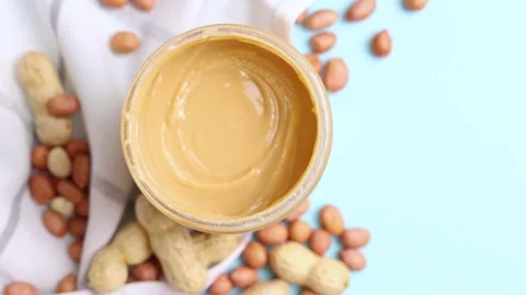peanut butter and raw peanuts on a color... | Stock Video | Pond5