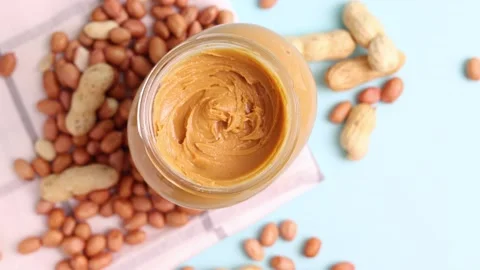 peanut butter and raw peanuts on a color... | Stock Video | Pond5