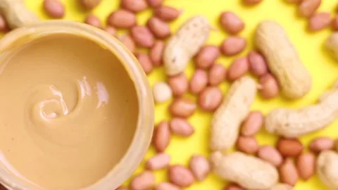 peanut butter and raw peanuts on a color... | Stock Video | Pond5