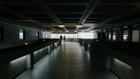People walking under a building in a cor... | Stock Video | Pond5