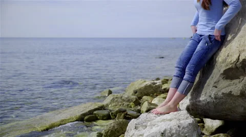 Person barefoot leaning on rock sunbathi... | Stock Video | Pond5