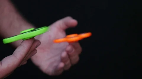 A person playing with two fidget spinner... | Stock Video | Pond5