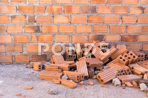 Pile of bricks in construction site with brick wall background Stock ...