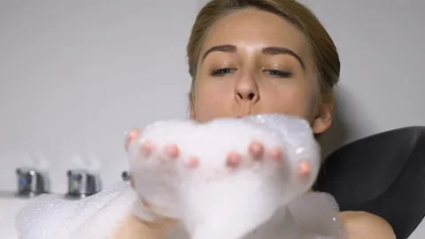 Playful young lady blowing on foam in ba... | Stock Video | Pond5
