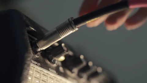 Plugs instrument cable into a guitar amp... | Stock Video | Pond5