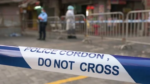 Police cordon tape is seen in the foregr... | Stock Video | Pond5