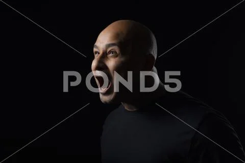 Portrait of a bald man screaming against dark black background. Stock ...