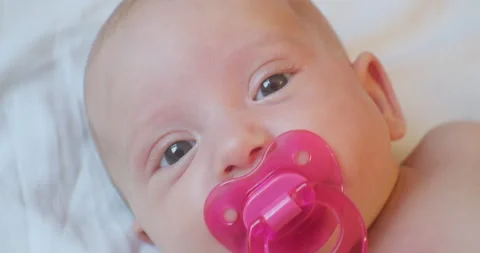 Portrait of a cute baby with a pink paci... | Stock Video | Pond5