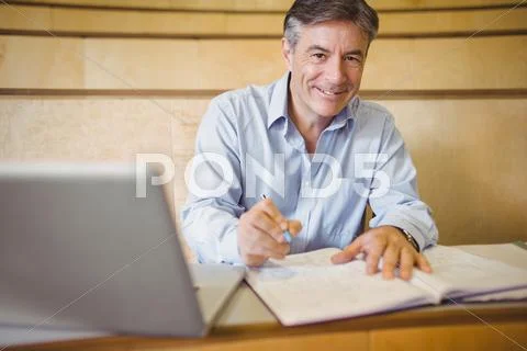 Portrait of happy professor writing in book at desk Stock Photo #62178020