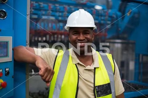 Photograph: Portrait of smiling factory worker leaning on machine ...