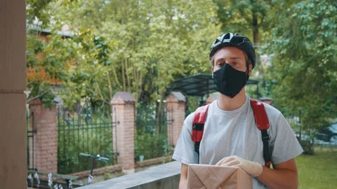 Postman in mask and helmet delivering pa... | Stock Video | Pond5