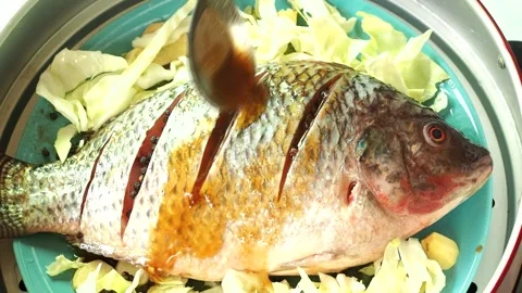 Pouring sauce on tilapia fish before s... | Stock Video | Pond5