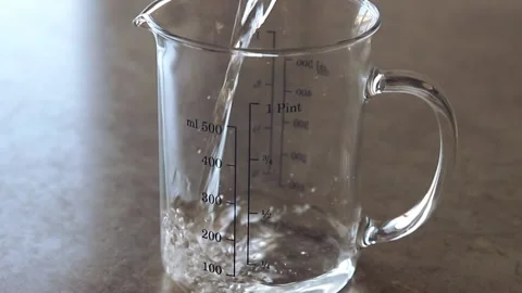 Pouring water into a measuring cup | Stock Video | Pond5