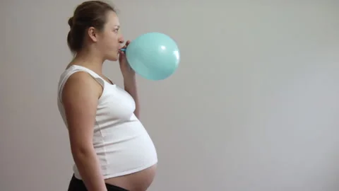 Pregnant woman blowing up a blue balloon | Stock Video | Pond5