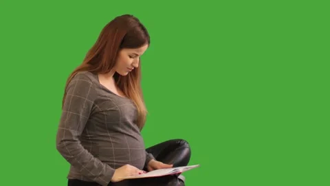 pregnant woman reading on a green screen | Stock Video | Pond5