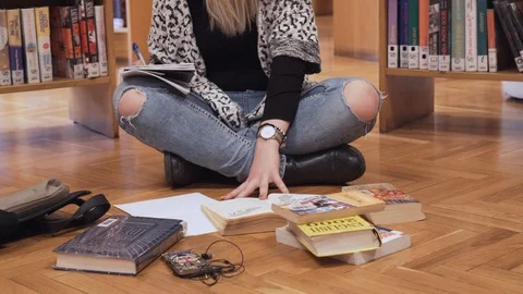 Pretty girl sitting on floor in library,... | Stock Video | Pond5