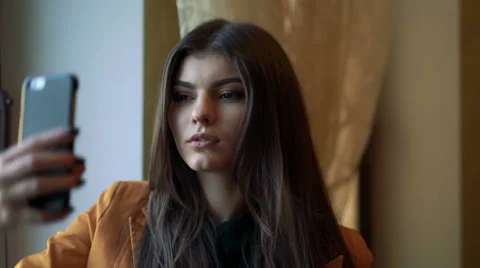 Pretty girl taking selfie at the window | Stock Video | Pond5