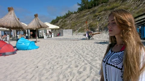 pretty lady at beach with huts and peopl... | Stock Video | Pond5