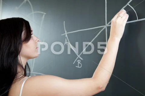 Pretty young teacher drawing on the chalkboard/blackboard during Stock ...