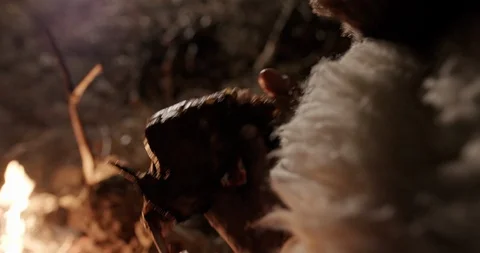 Primitive man eating meat near fire | Stock Video | Pond5