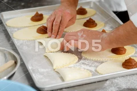 Puff pastry with jam filling. Bakery worker is making a small batch ...