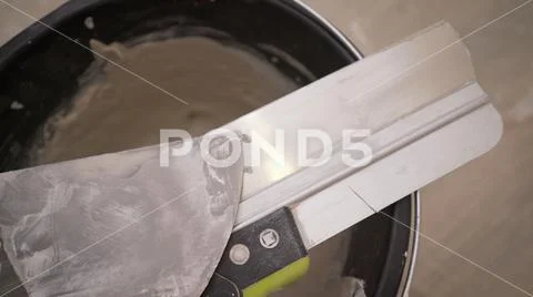 Photograph: Putty knife in a steel bucket. Spatulas on a bucket when ...