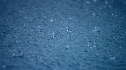 Rain drops falling on puddle water close... | Stock Video | Pond5