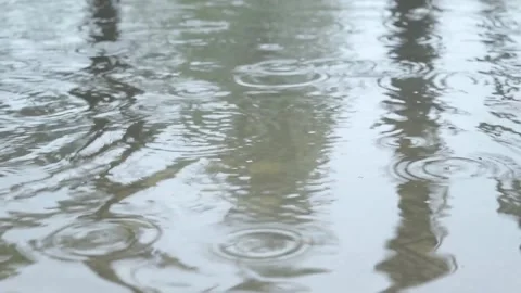 Rain drops falling on water surface. Clo... | Stock Video | Pond5
